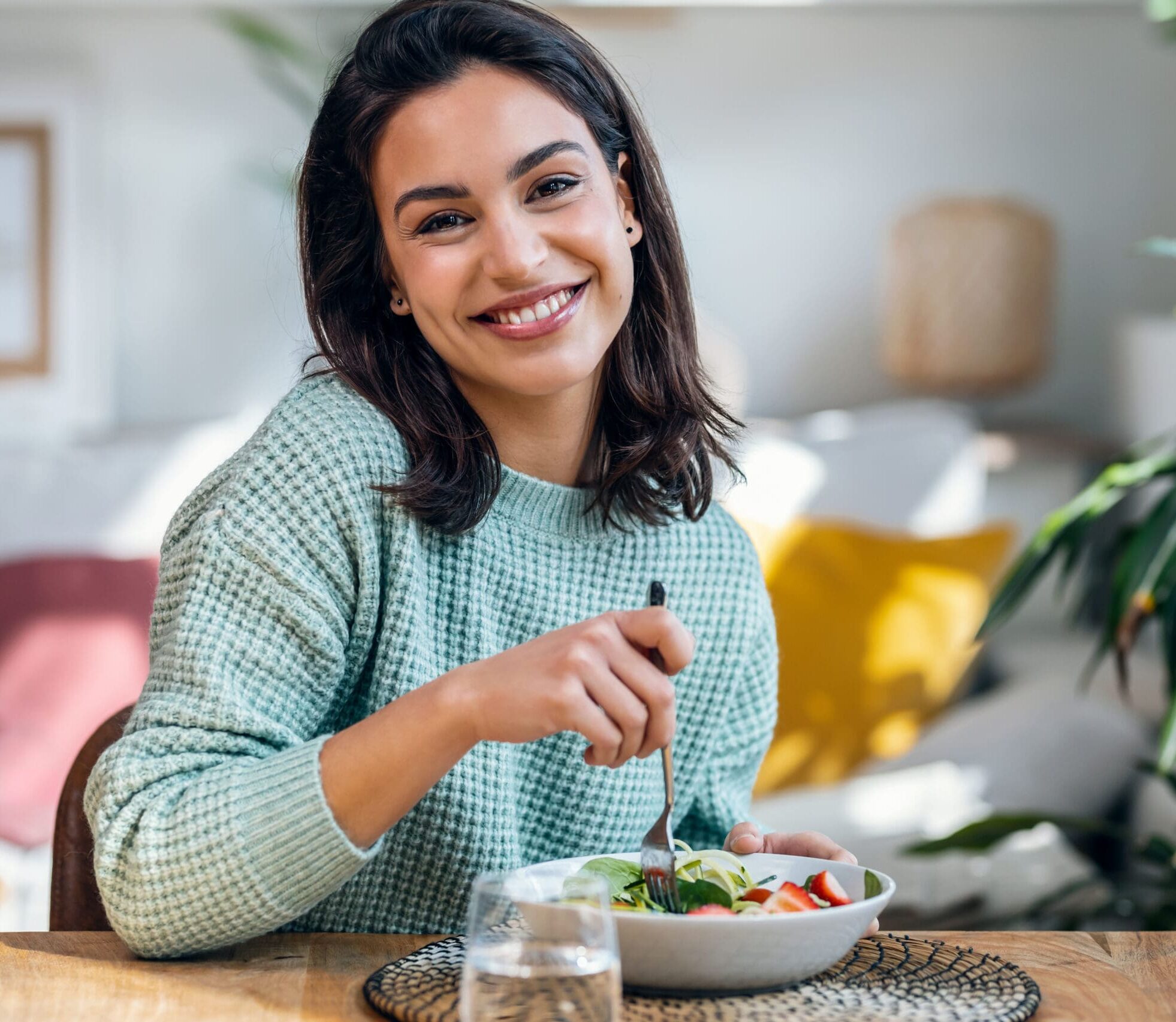 Beautiful smiling woman eating healthy while looking at camera a ...