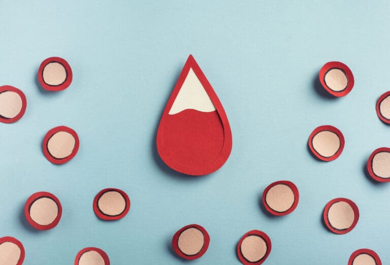 Drop of blood and red blood cells on pastel blue background. Iron ...